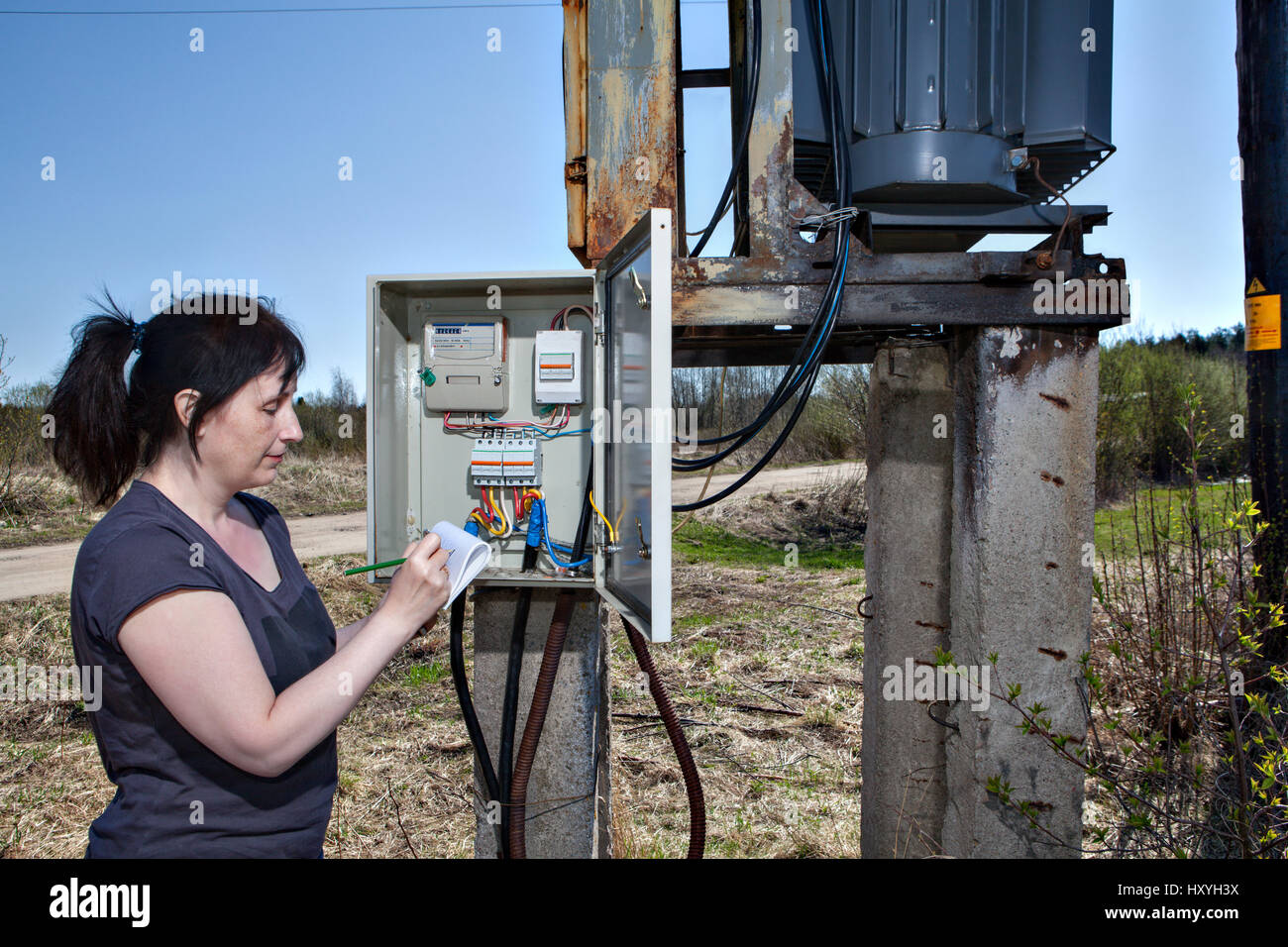Technician woman checking electricity meter and invoice, standing near ...