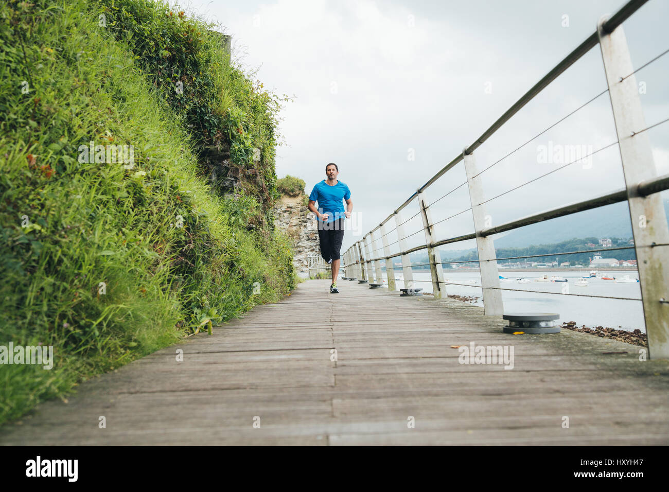 Attractive man running on a wooden walkway next to the sea. Daily ...