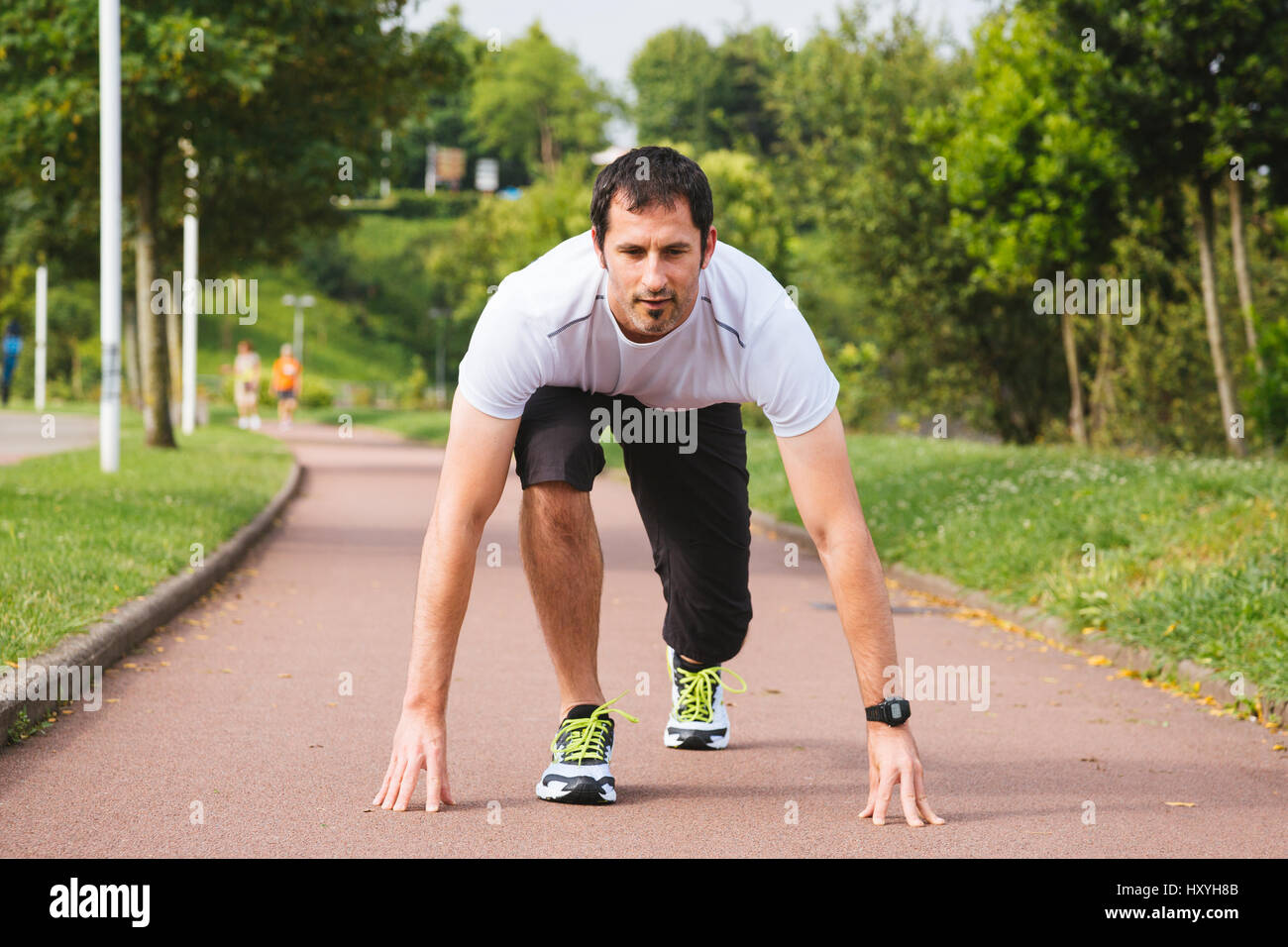 Attractive sportsman ready to sprint in a sports area outdoors Stock ...