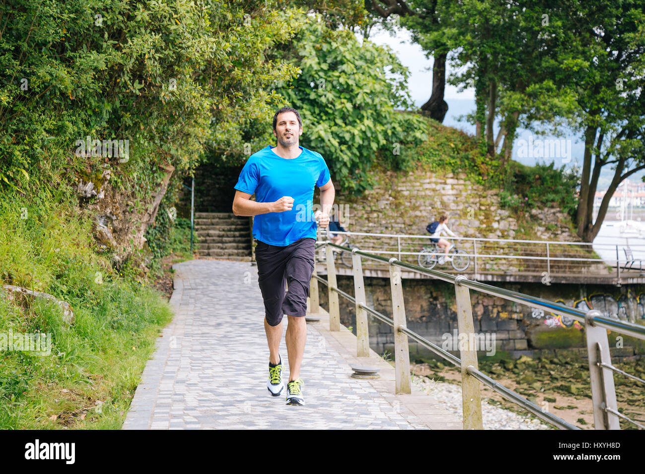Attractive man running on a walkway next to the sea. Daily training ...