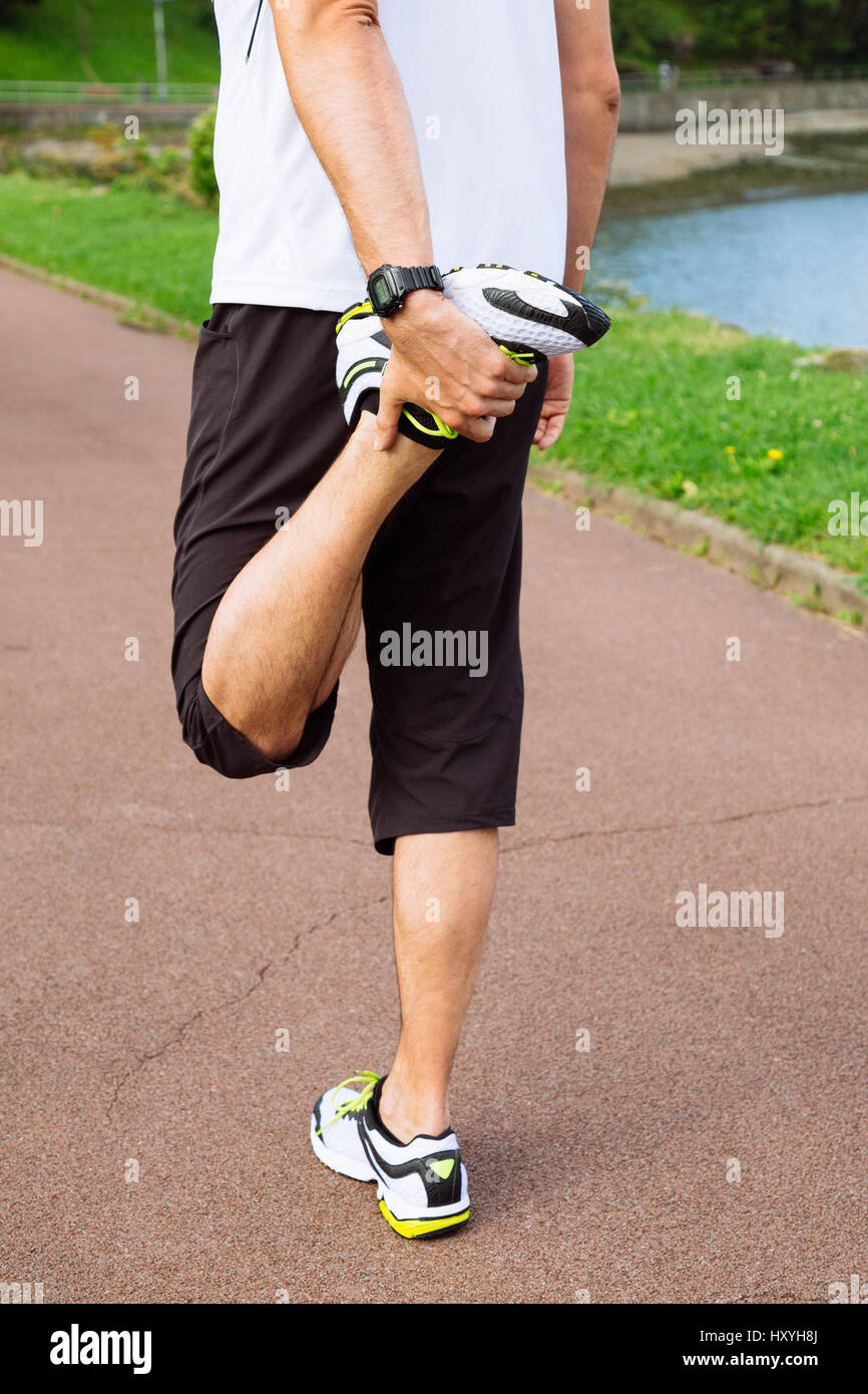 Legs of sportsman doing stretching exercises outdoors in a track before ...