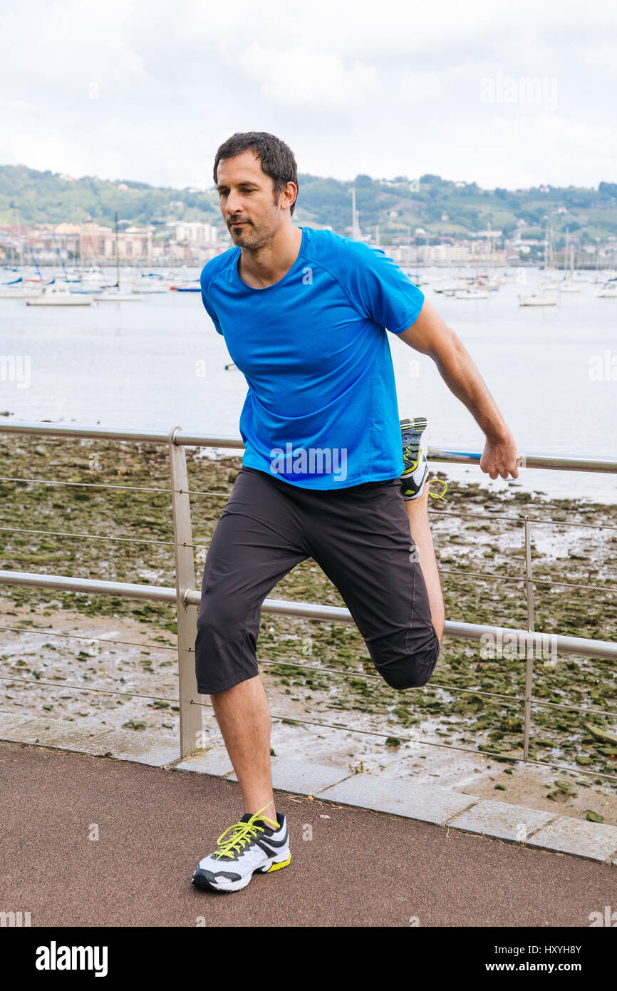 Attractive sportsman doing stretching exercises outdoors in a track ...