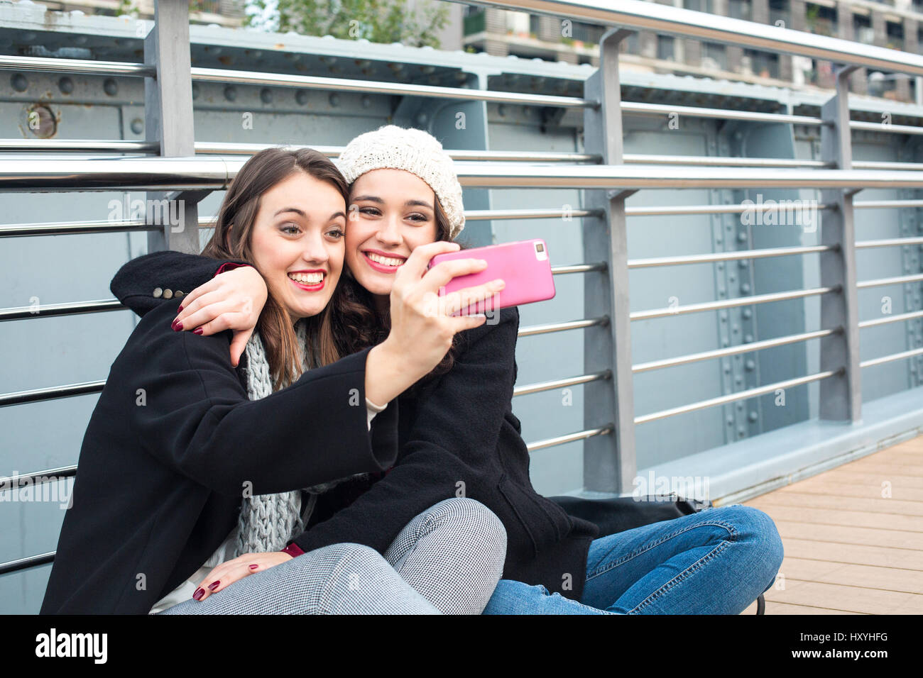 Cute female friends posing for a selfie outdoors sitting in the floor ...