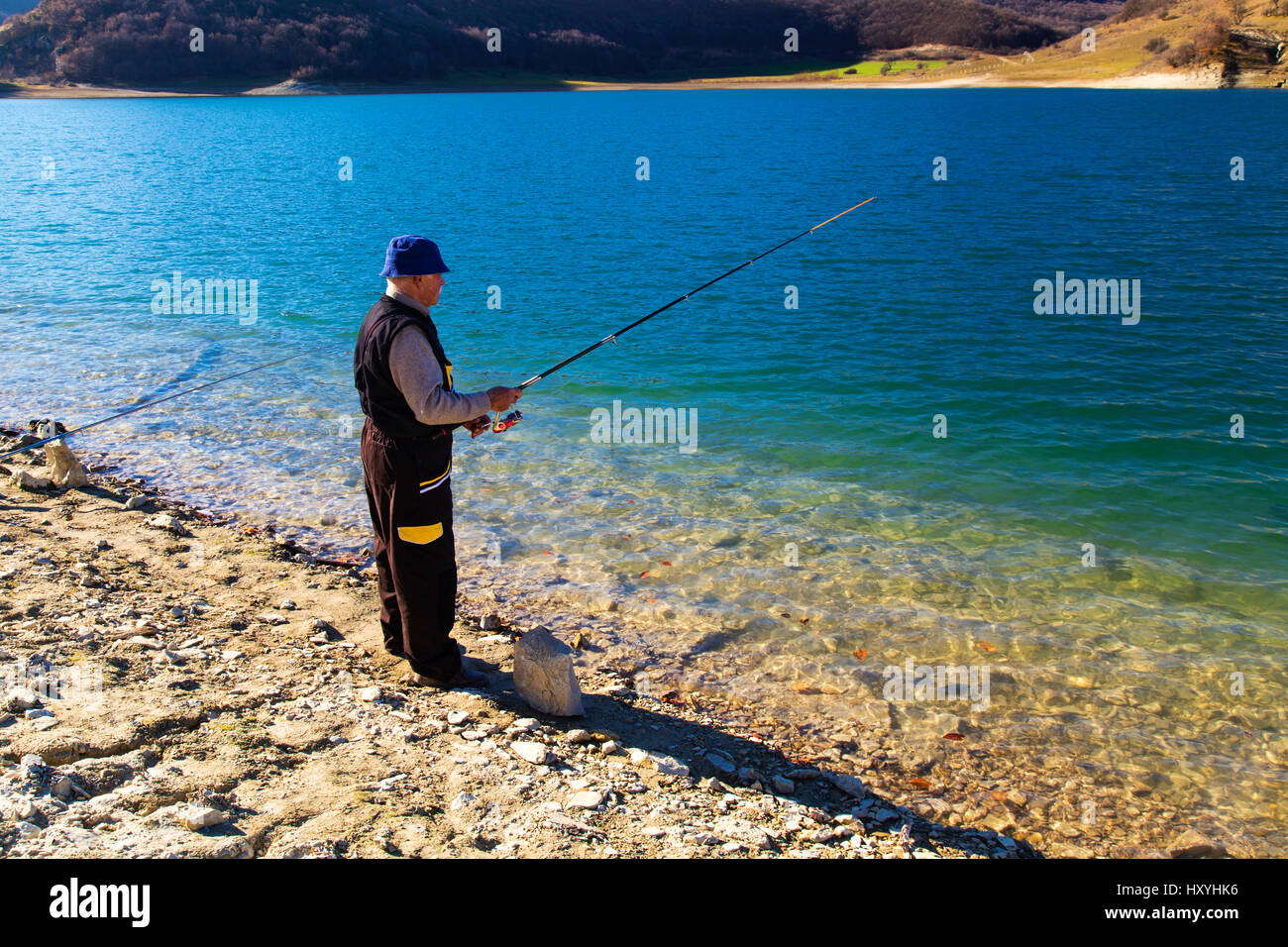 Fisherman fishing on beautiful blue lake Stock Photo - Alamy
