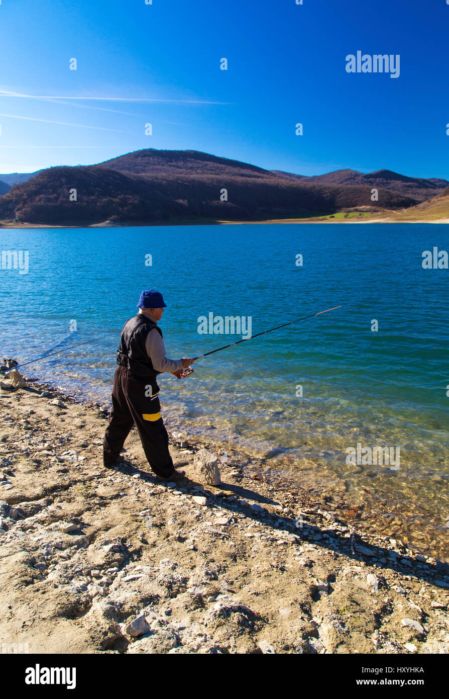 Fisherman fishing on beautiful blue lake Stock Photo - Alamy