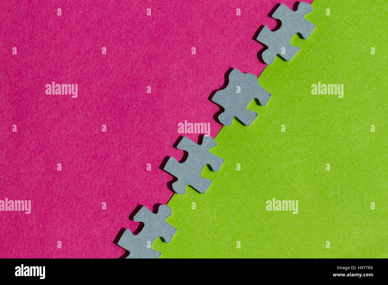 Jigsaw Puzzle pieces on border between pink and green background with ...