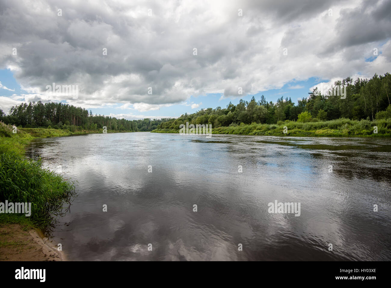 calm river in forest with reflections and trees on both sides of the ...