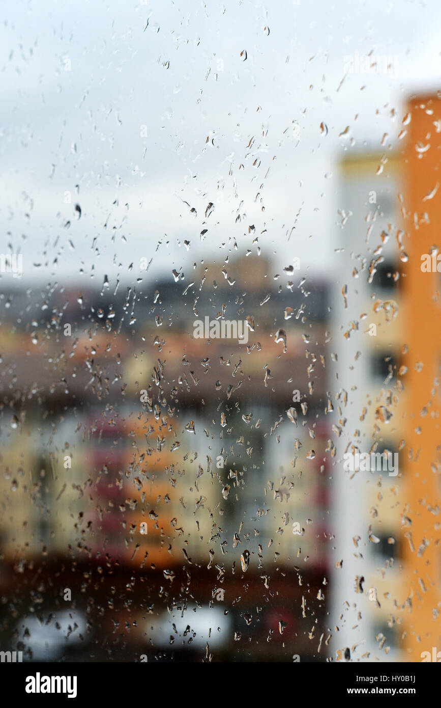 Rain drops on the window in the city with building on the background ...