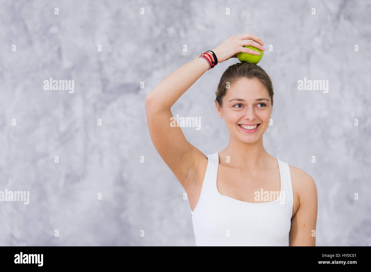 Smiling woman doing yoga pose holding apple on her head Stock Photo - Alamy