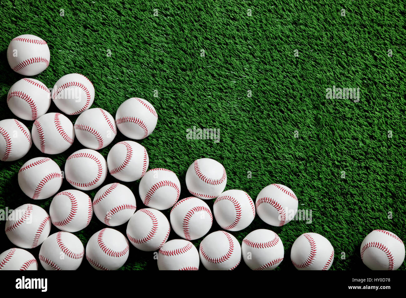 Several baseballs in the corner of a green turf background viewed from ...