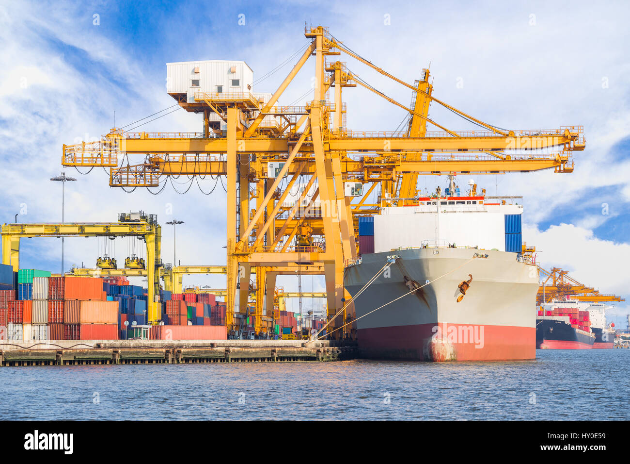 Container cargo freight ship with working crane loading bridge in ...