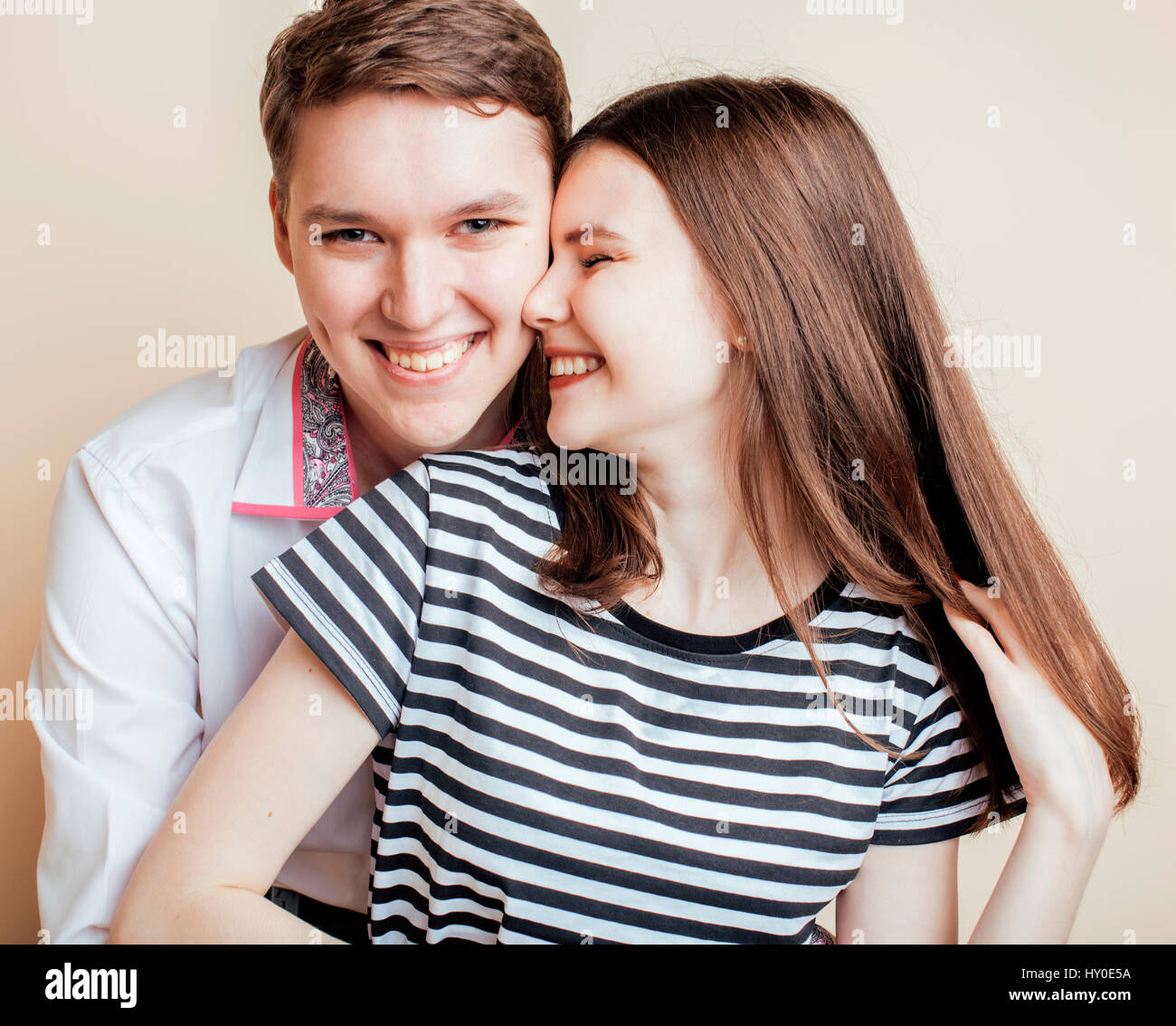 couple of happy smiling teenagers students, warm colors having a kiss ...