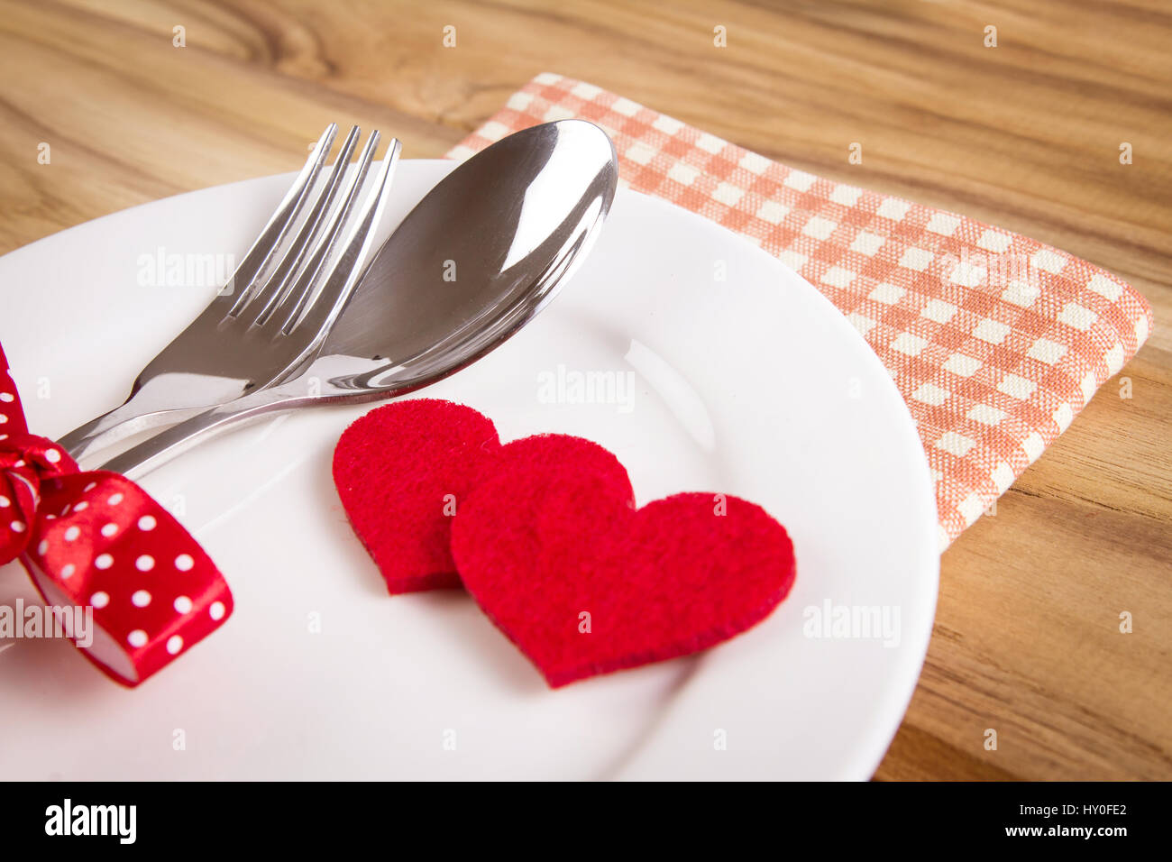 red heart shape with White empty plate with fork and spoon on wooden ...