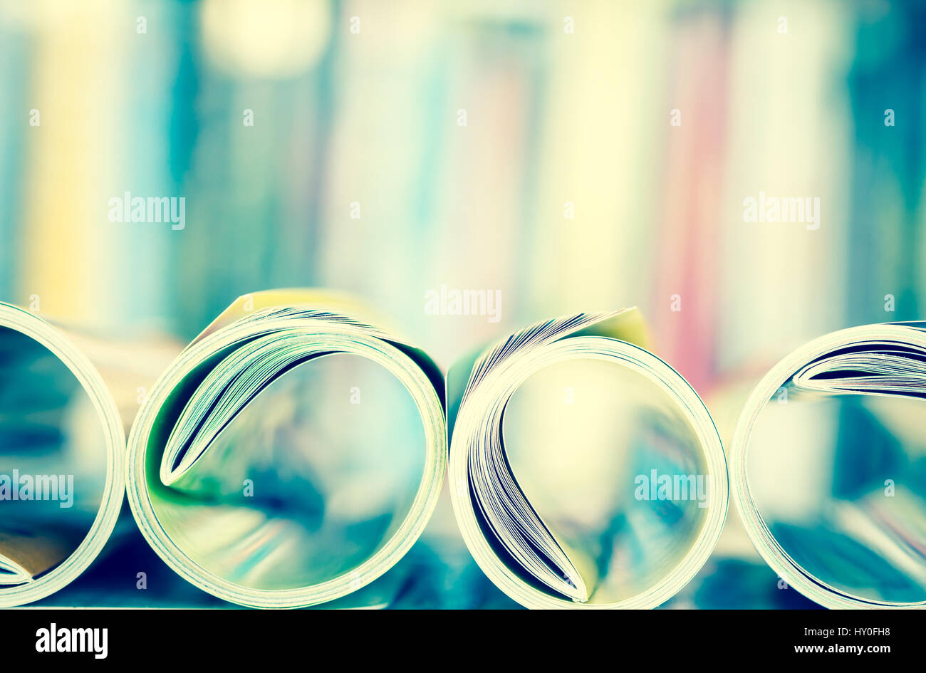 Close up edge of colorful magazine stacking roll with blurry bookshelf ...