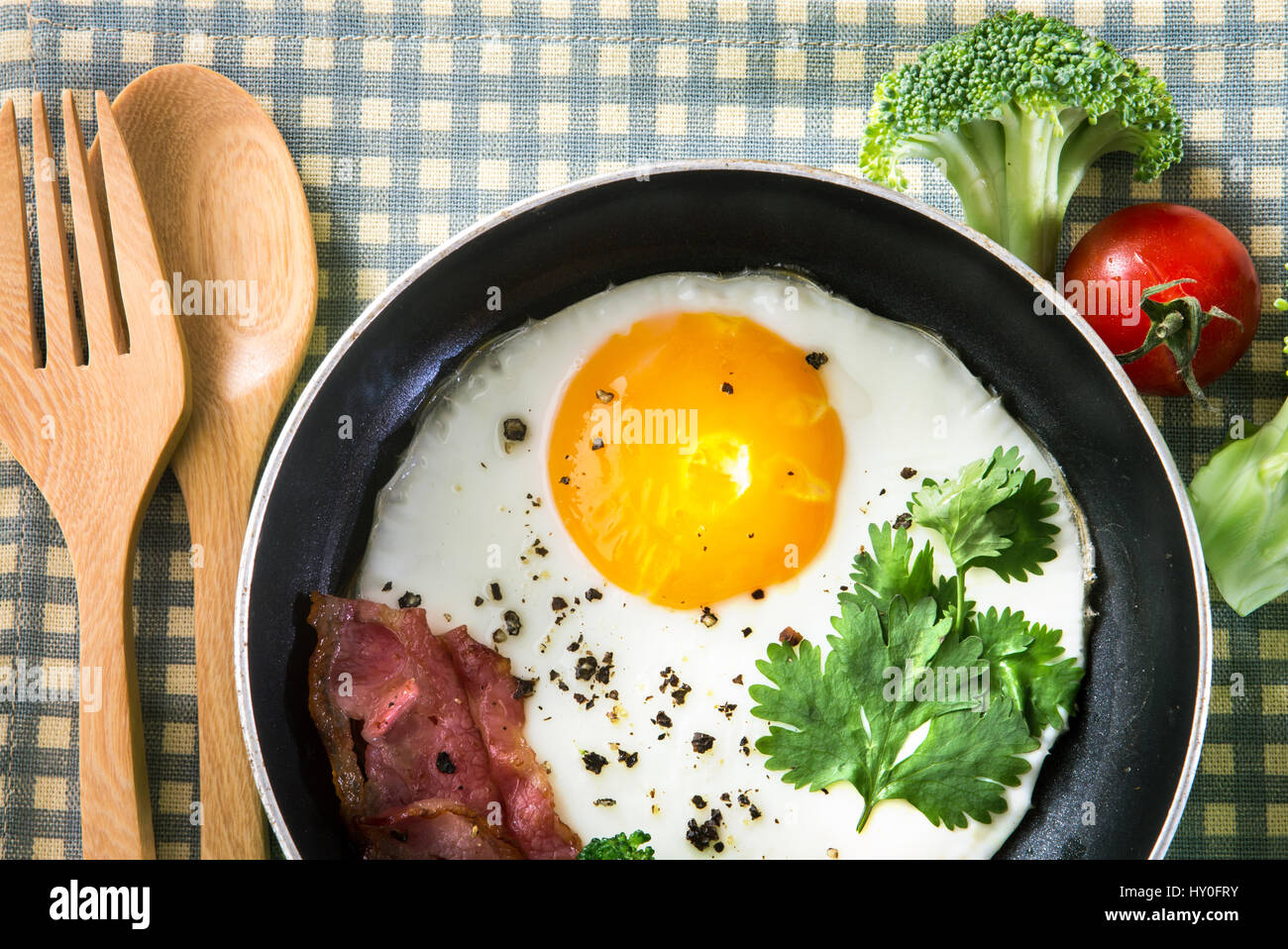 Breakfast with fried egg and bacon in dark pan on the table Stock Photo ...
