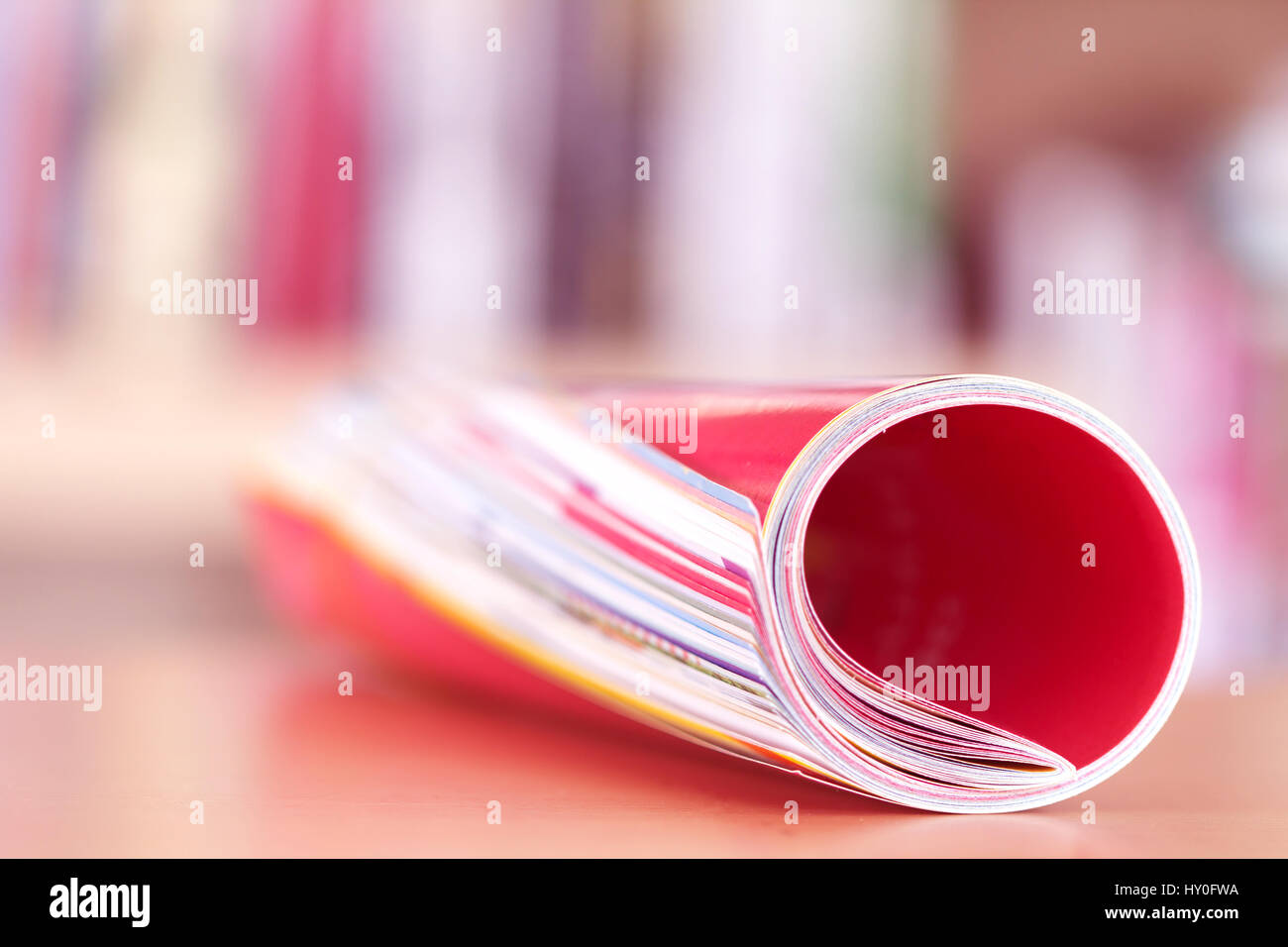 Close up edge of colorful magazine stacking roll with blurry bookshelf ...