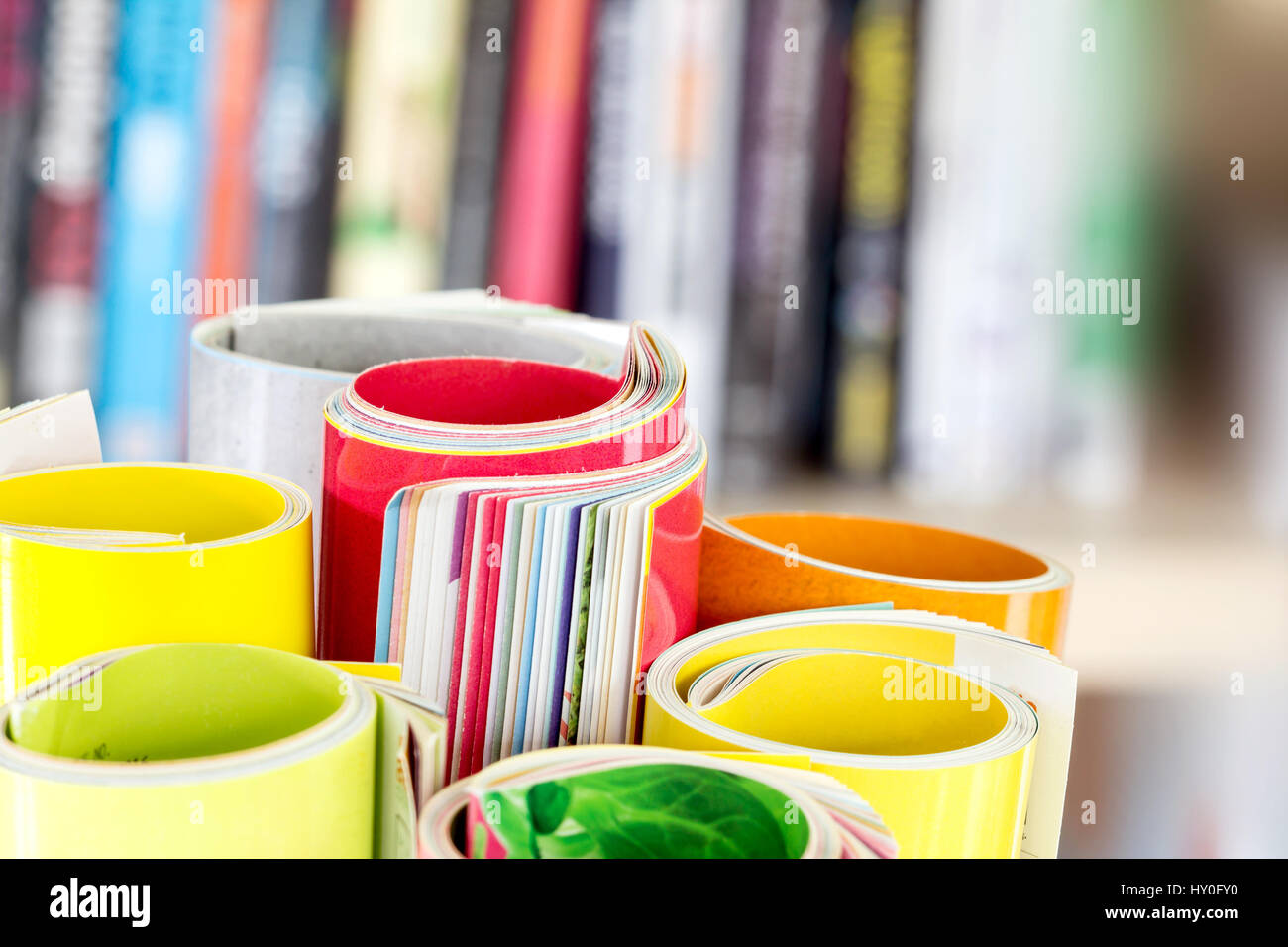 Close up edge of colorful magazine stacking roll with blurry bookshelf ...