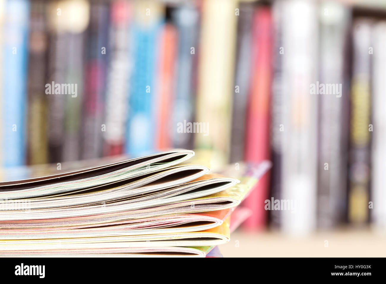 Close up edge of colorful magazine stacking with blurry bookshelf ...