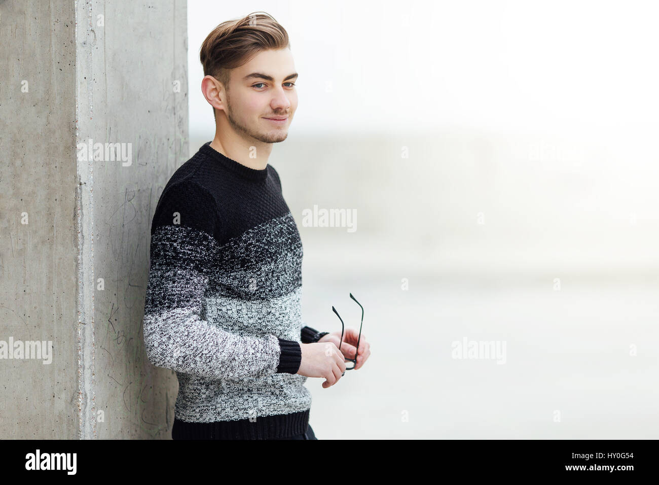 Fashionable man standing near wall with blur background Stock Photo - Alamy