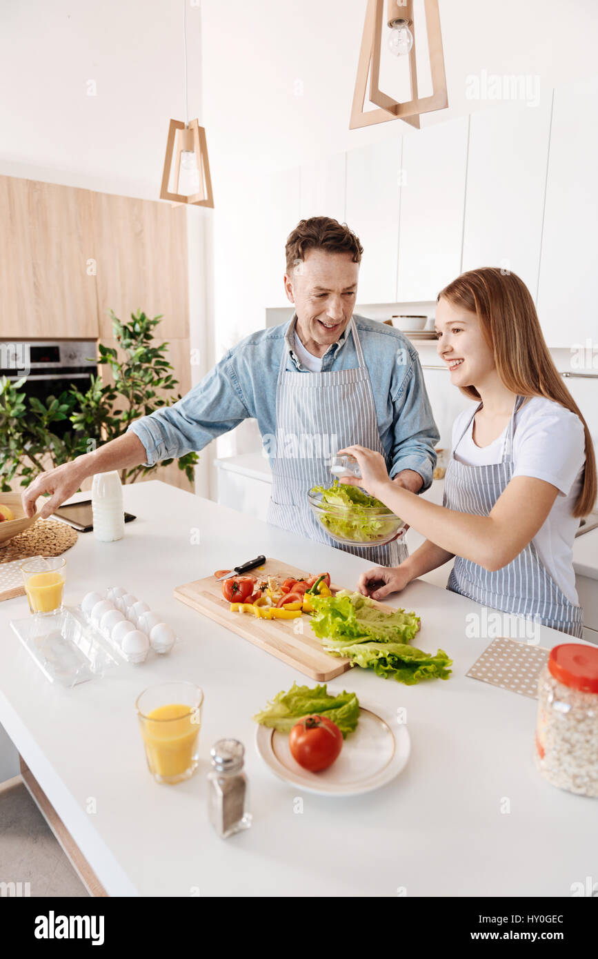 Make is tasty. Positive delighted girl and her smiling father seasoning ...