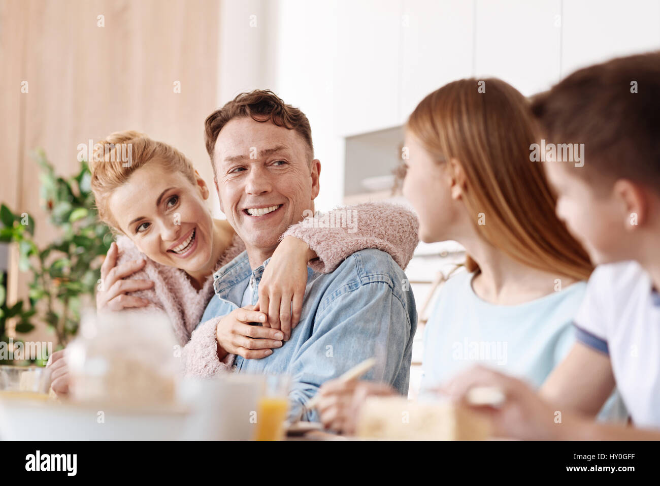 Proud of you. Cheerful smiling parents embracing and looking at their ...