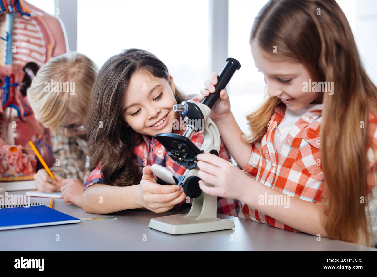 Excited creative classmates testing a microscope Stock Photo - Alamy