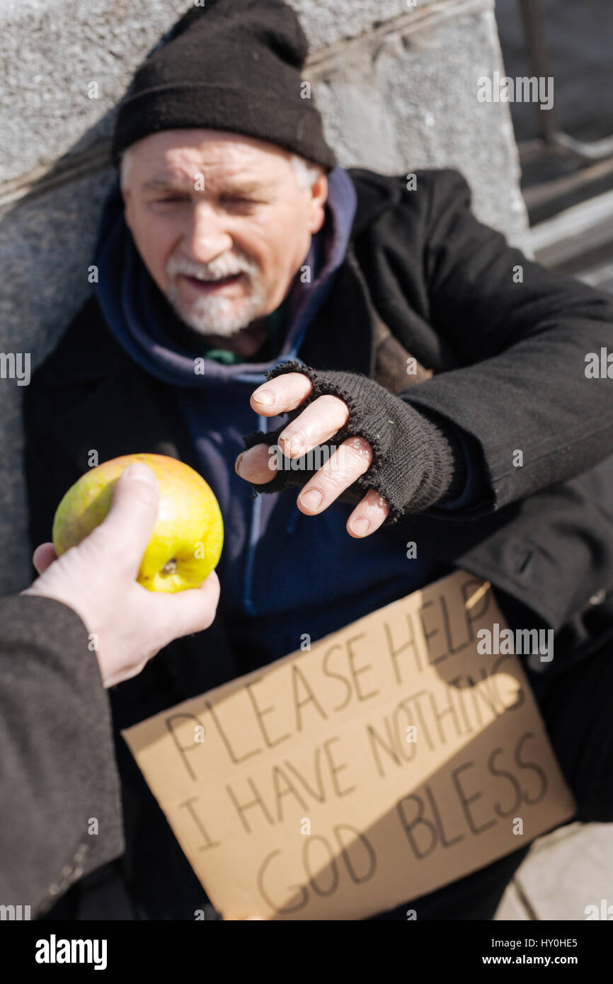 Needy elderly man taking apple Stock Photo - Alamy