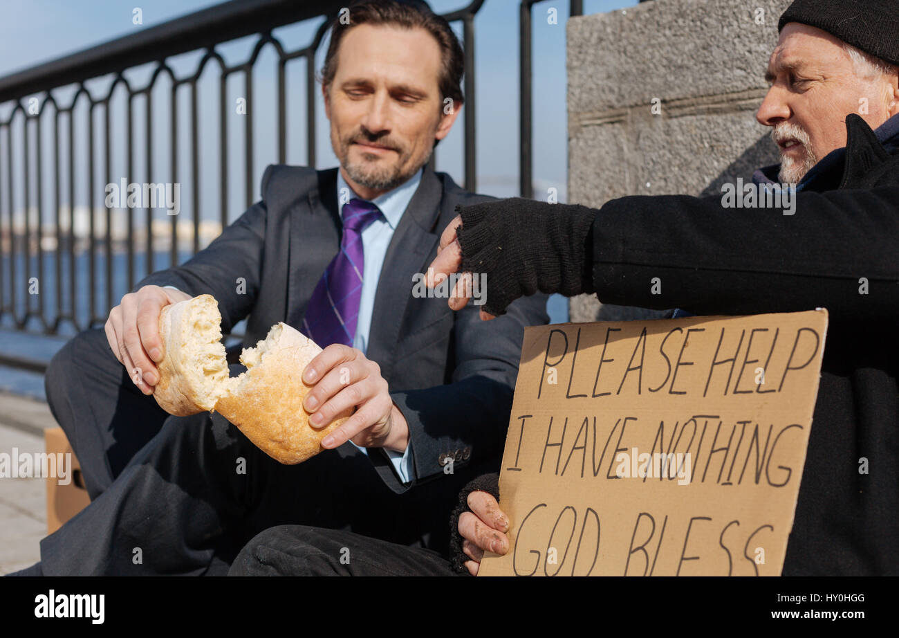 Positive delighted brunette sharing bread in two pieces Stock Photo - Alamy