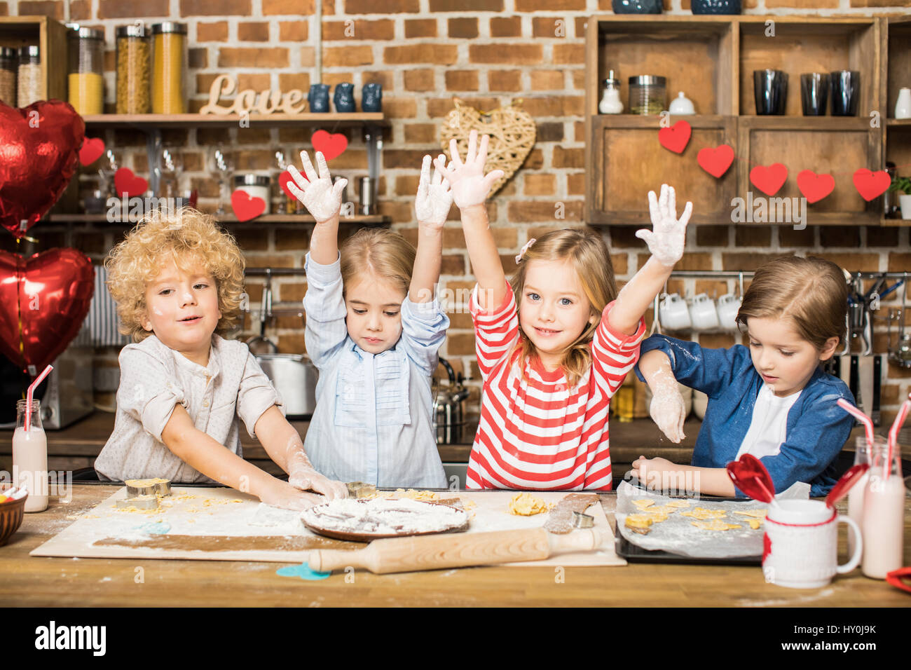 Four cute little children cooking biscuits and showing hands in flour ...