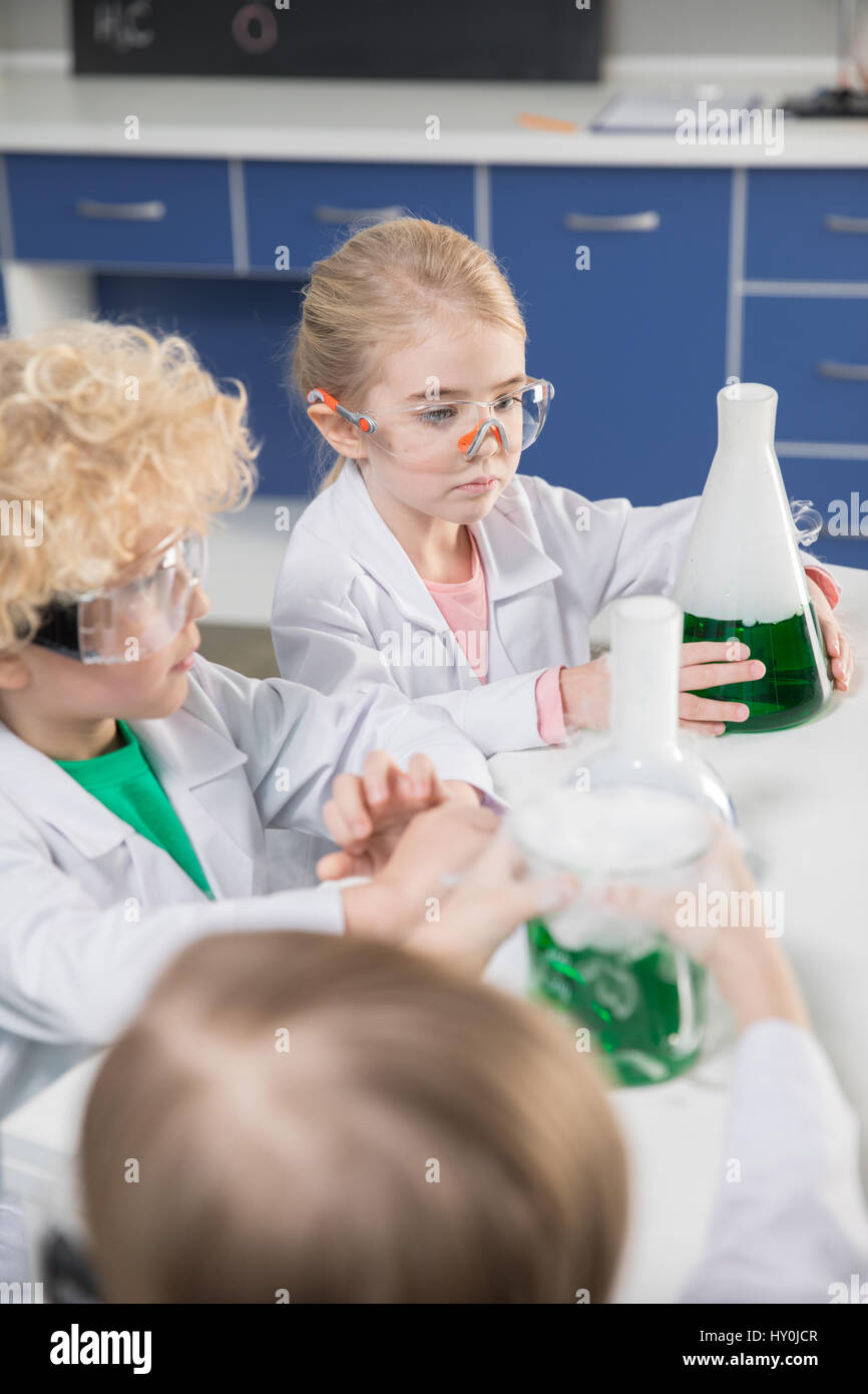 Kids in protective glasses and lab coats making experiment in chemical ...