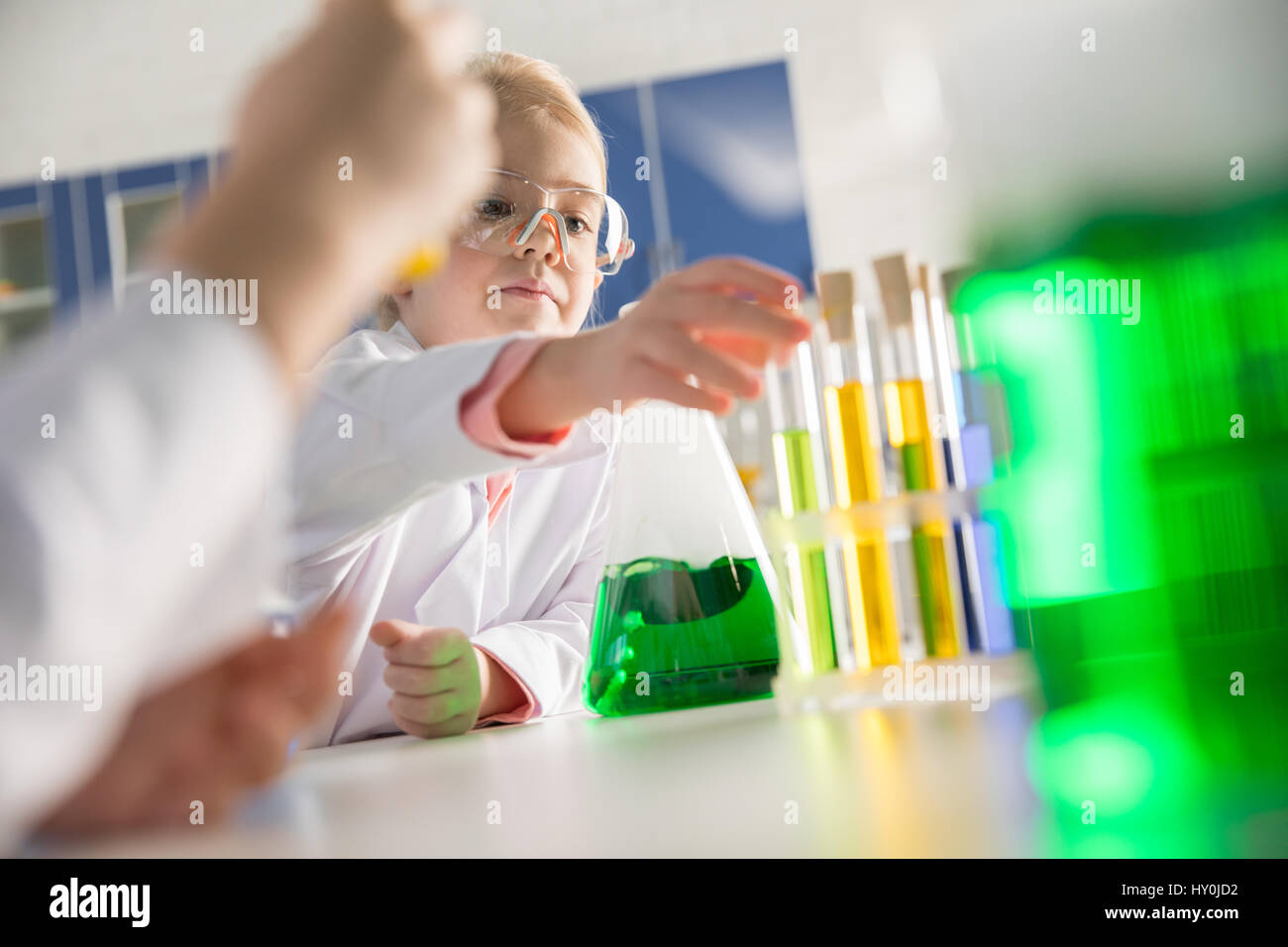 Schoolchildren in lab coats making experiment with test tubes in ...