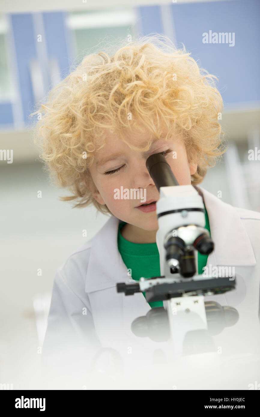 Little boy in lab coat looking through microscope Stock Photo - Alamy