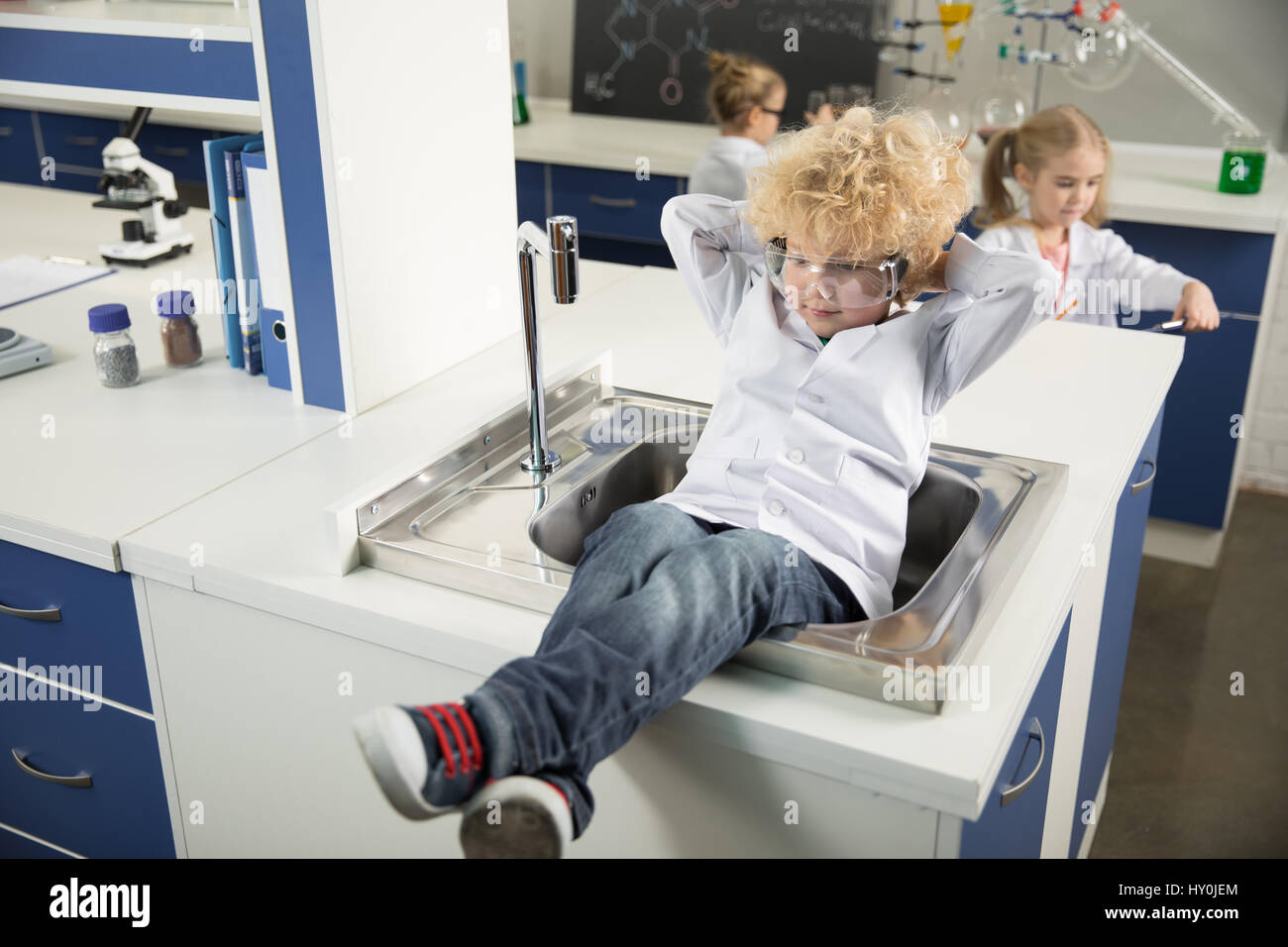 Relaxed little boy sitting in sink in science laboratory Stock Photo ...