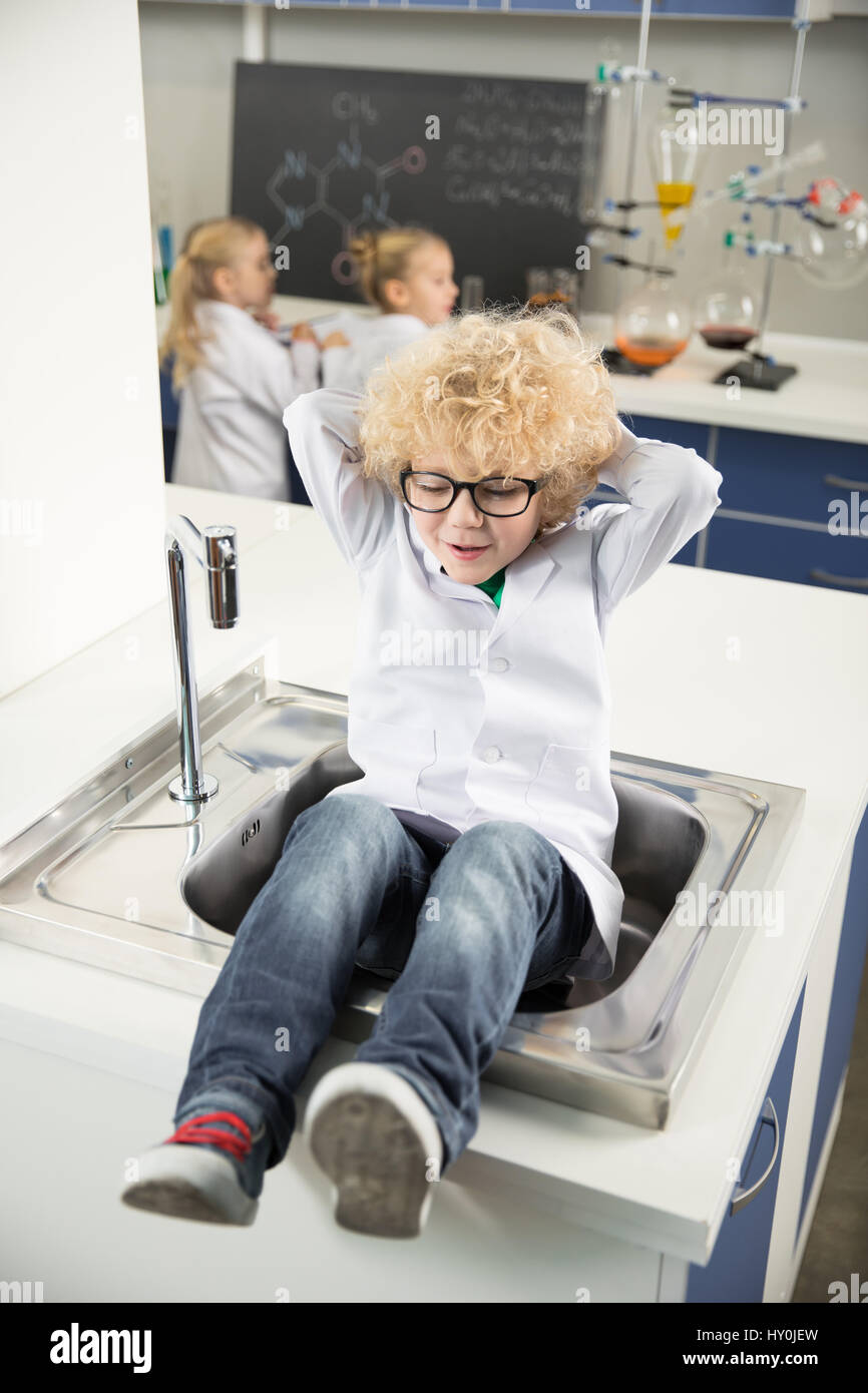 Relaxed little boy sitting in sink in science laboratory Stock Photo ...