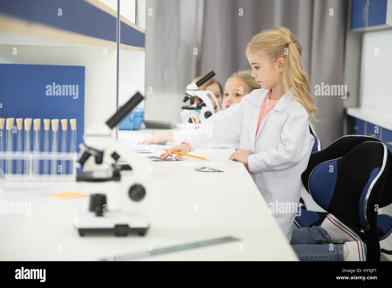 Little kids wearing lab coats and studying in science laboratory Stock ...