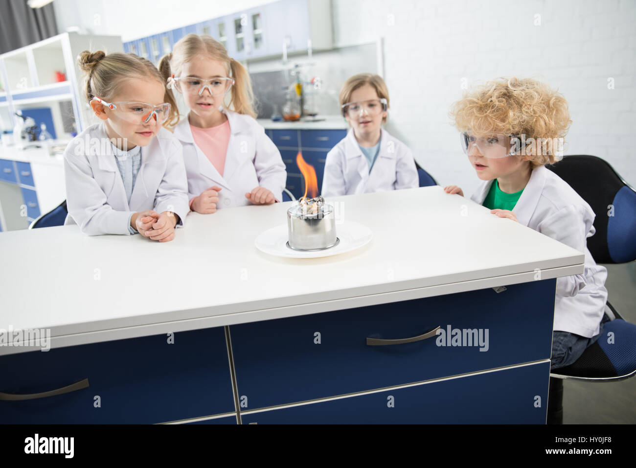 Kids in lab coats and protective glases making experiment in laboratory ...