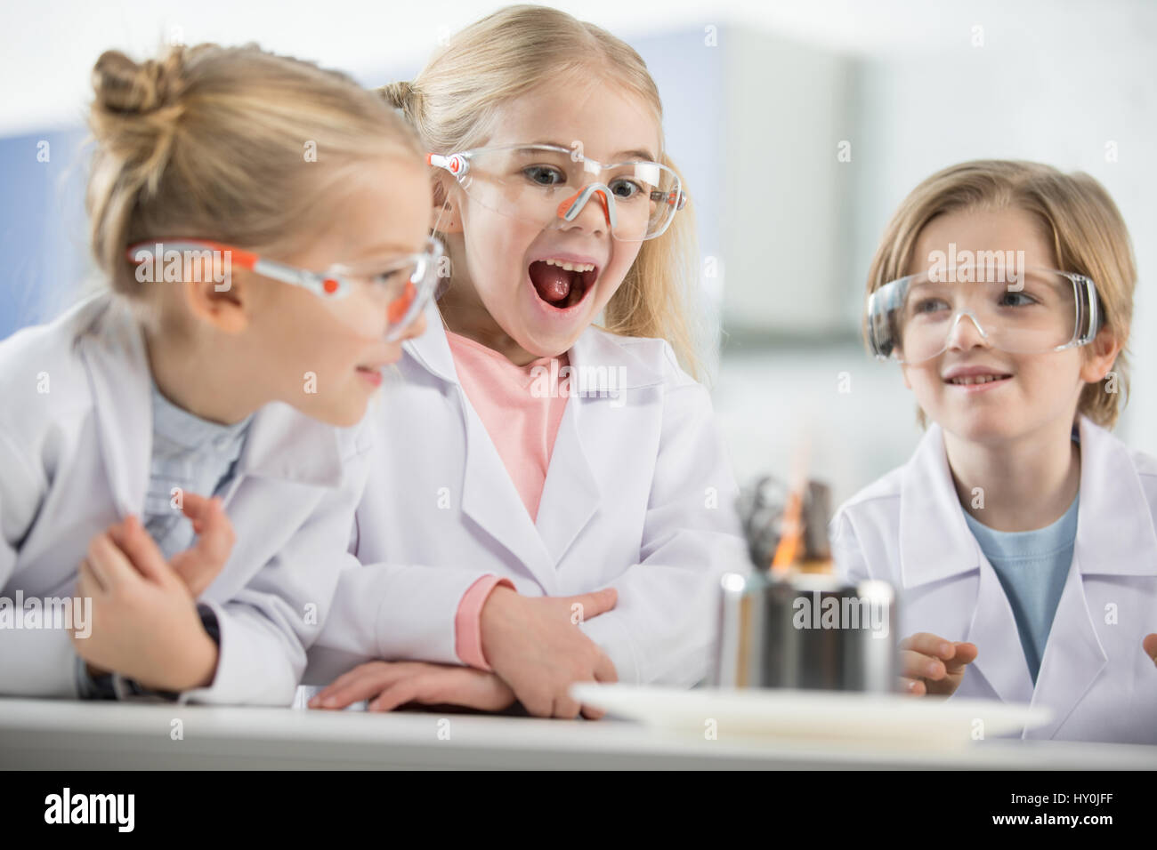 Three kids wearing protective glasses in science laboratory Stock Photo ...