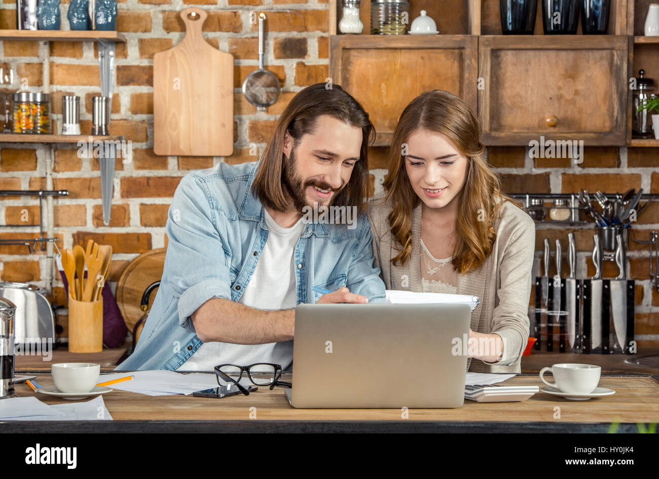 Smiling young couple working with documents and laptop at home Stock ...