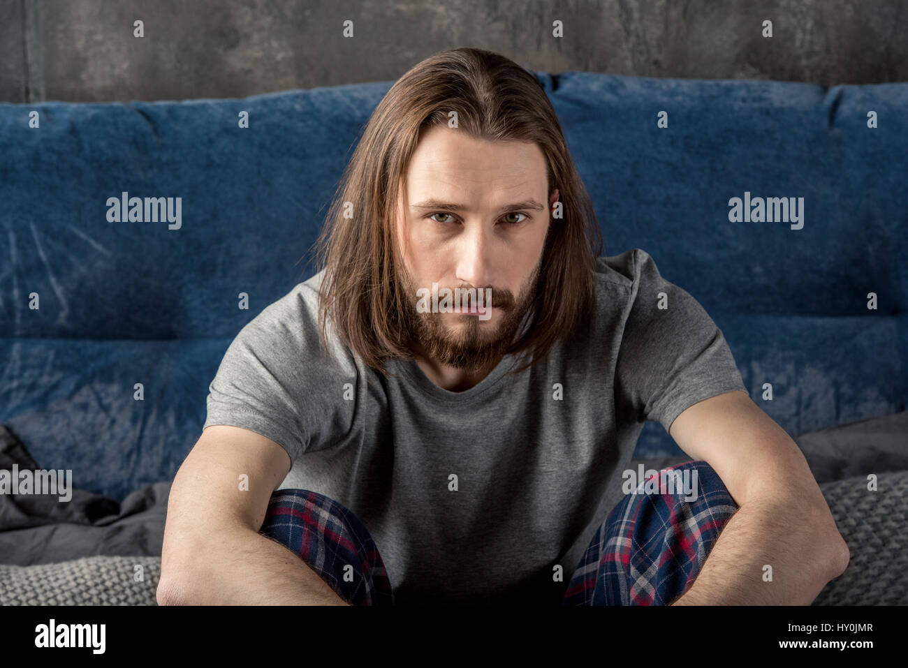 Serious bearded man sitting in bed and looking at camera Stock Photo ...