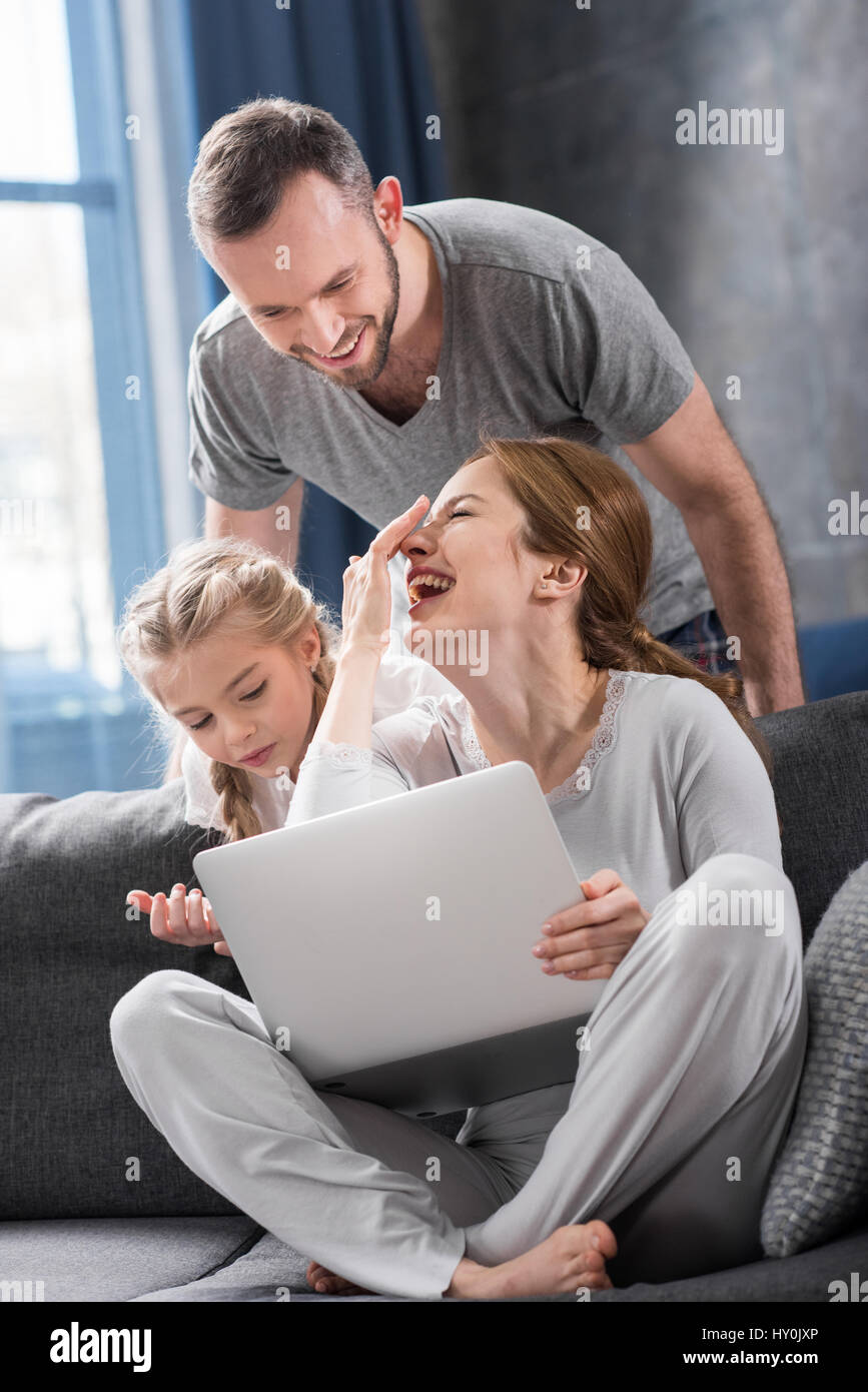Happy family using laptop together and laughing Stock Photo - Alamy