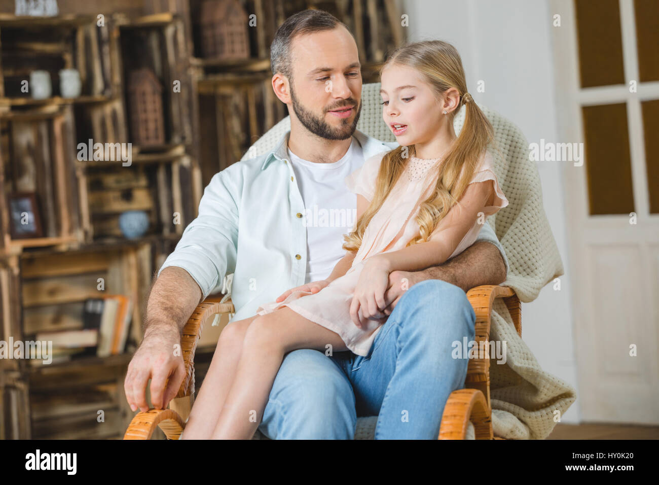 Smiling Father And Daughter Sitting Together In Rocking Chair Stock