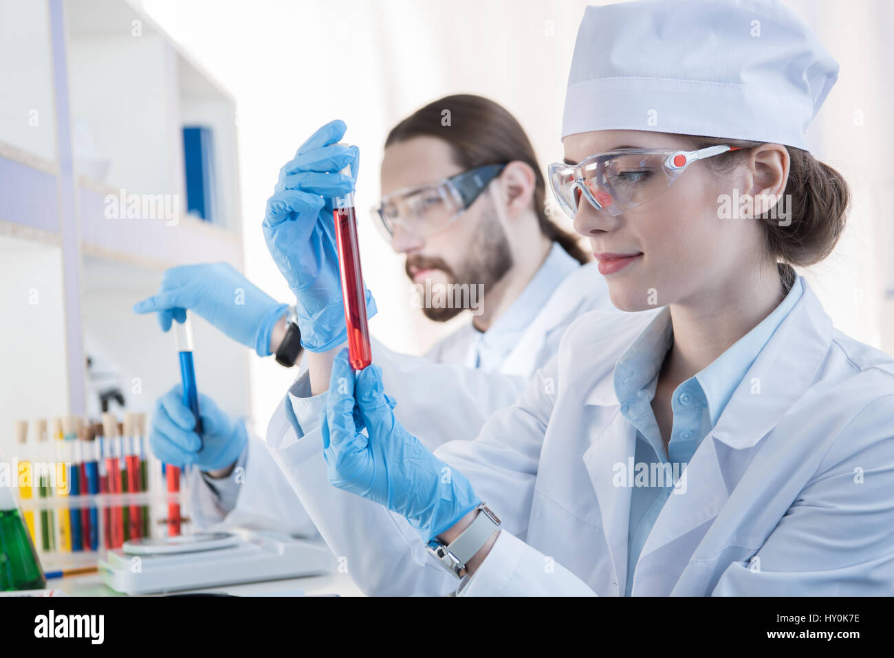 Professional chemists making experiment with reagents in test tubes ...
