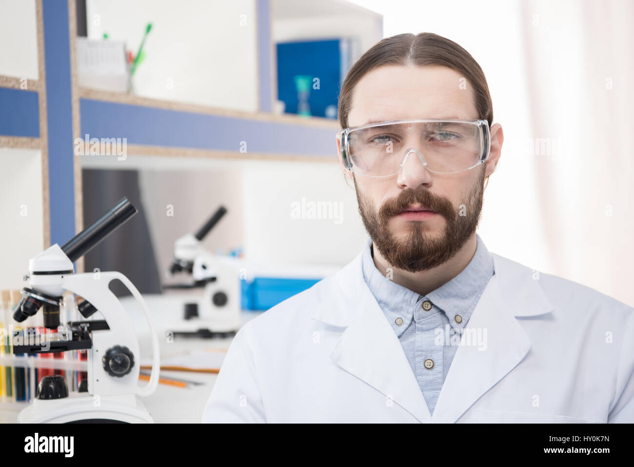 Professional male scientist in protective goggles looking at camera ...