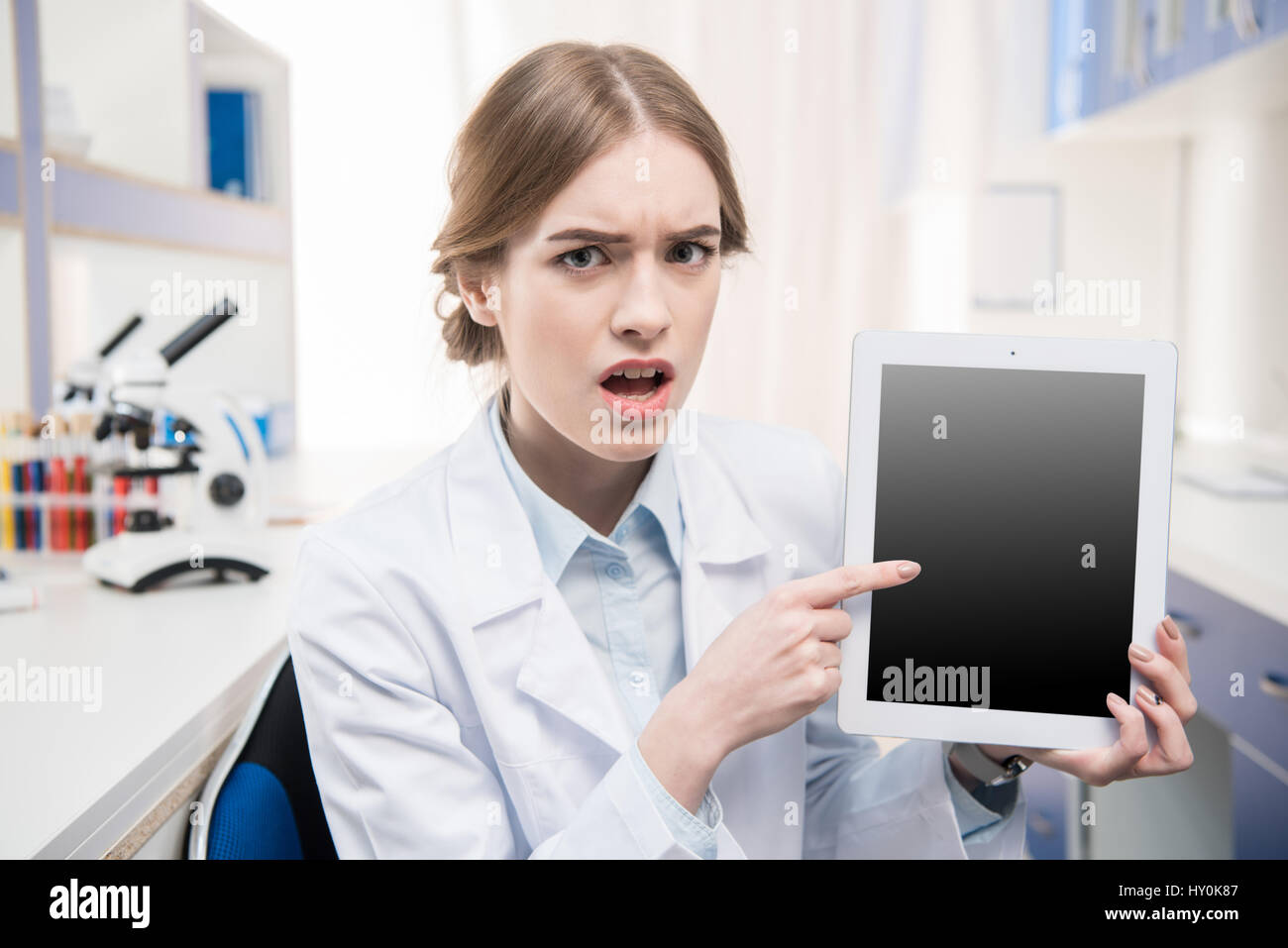 Shocked female scientist showing digital tablet in lab Stock Photo - Alamy
