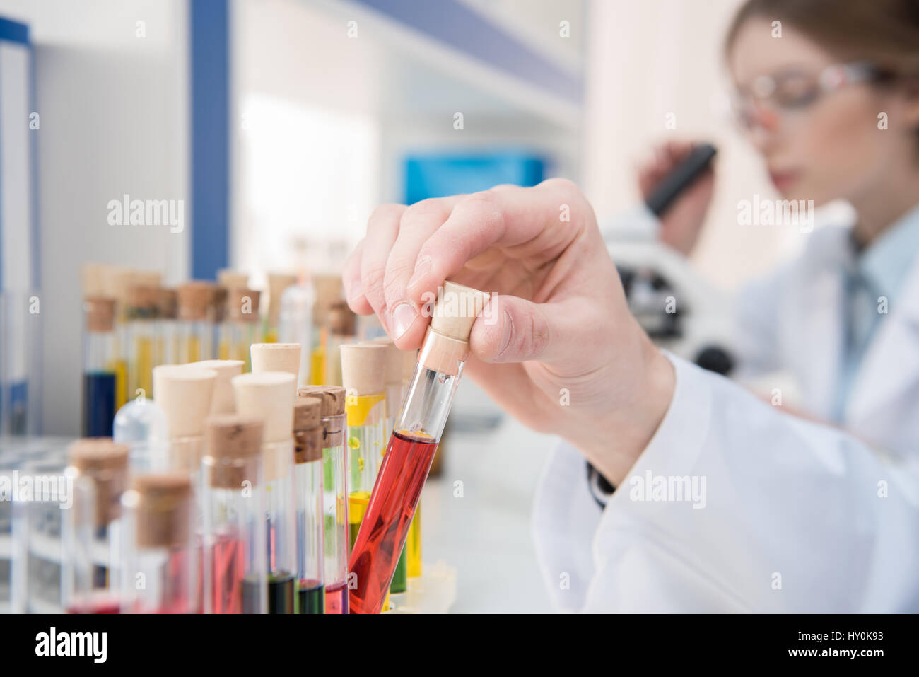 Close-up view of test tubes with different reagents and hand of ...