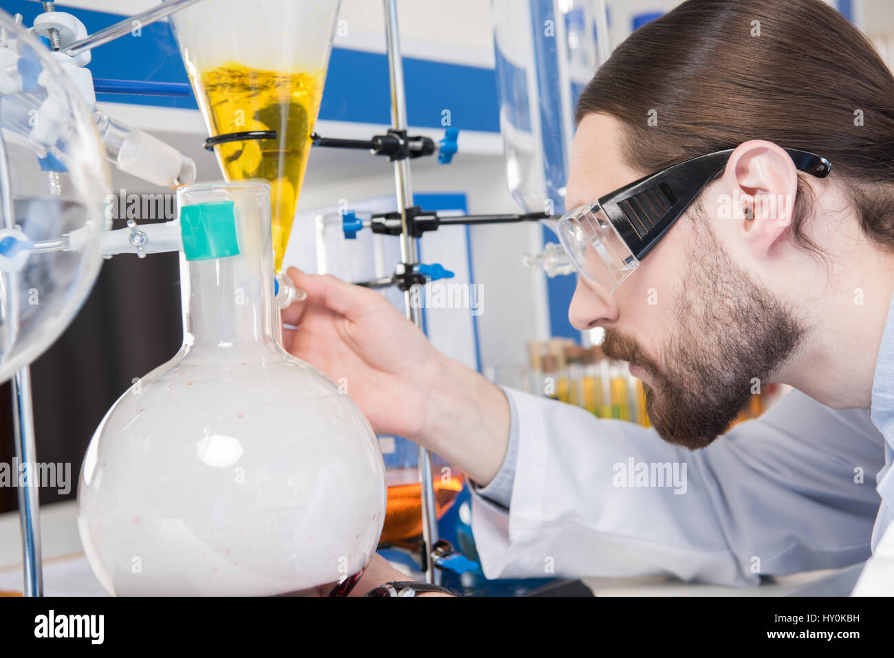 Young male scientist in protective glasses making experiment in ...