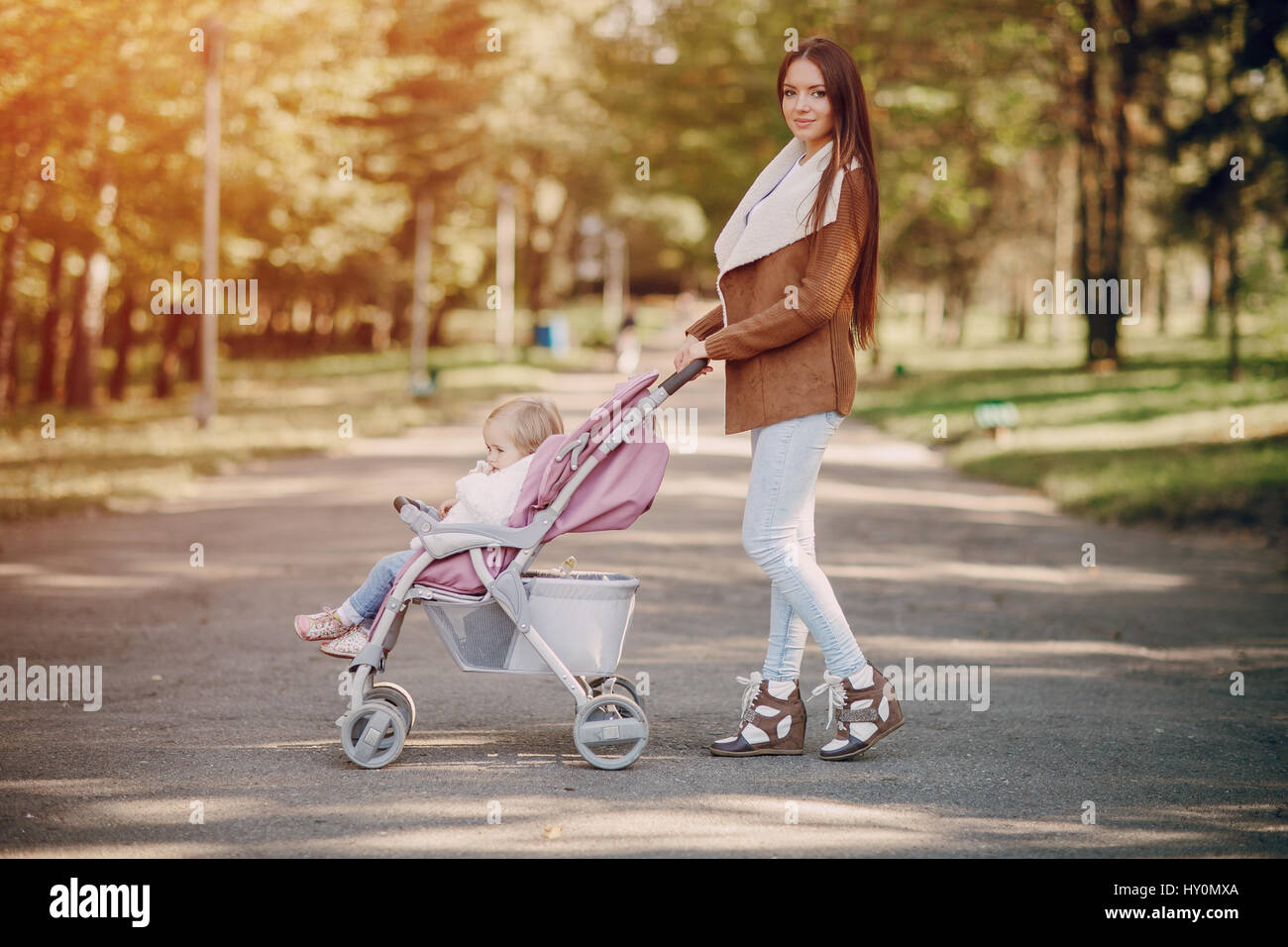 young mother walking with her baby and carries it in a beautiful pram ...
