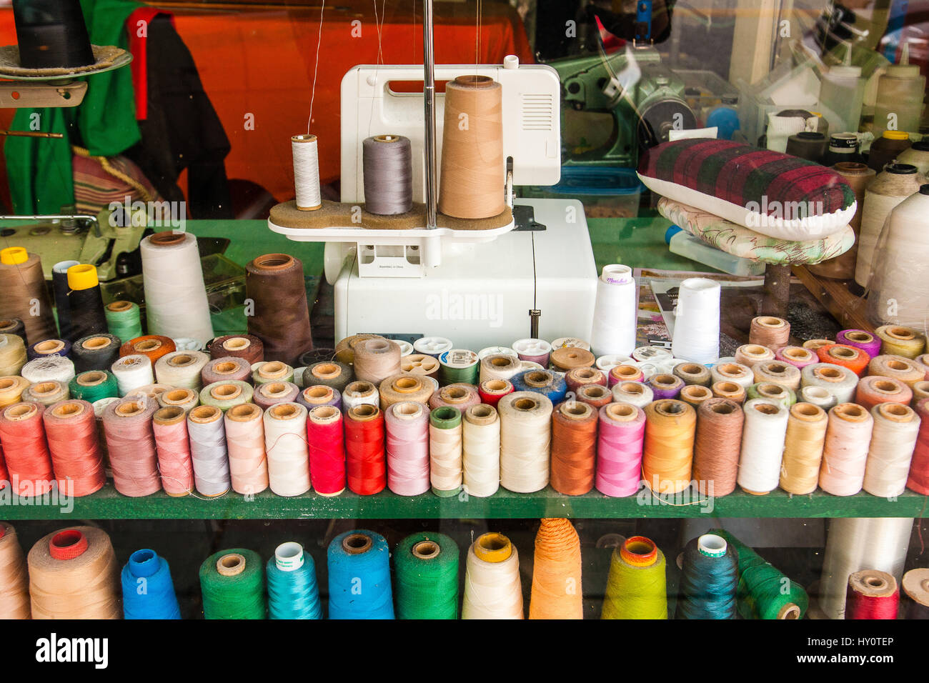 Spools of colorful thread and sewing machine in window of tailor shop ...