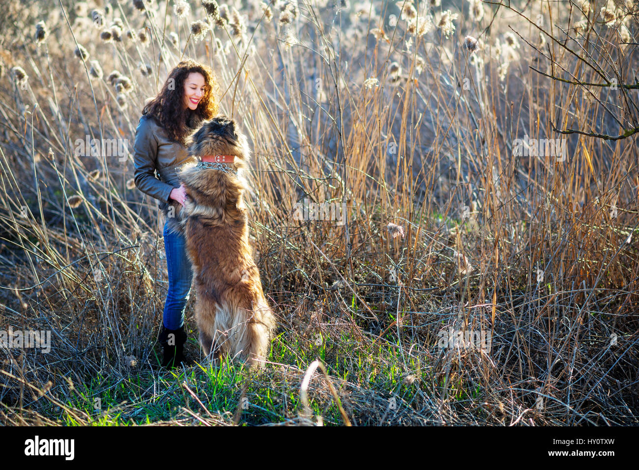 Young woman playing with Caucasian shepherd in a delightful spring day ...