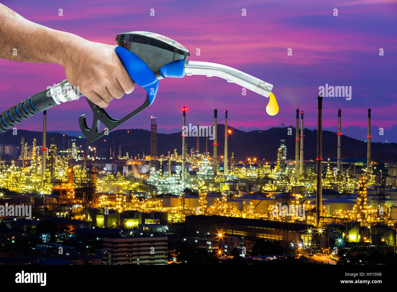 Hand holding a fuel nozzle with refinery background Stock Photo - Alamy